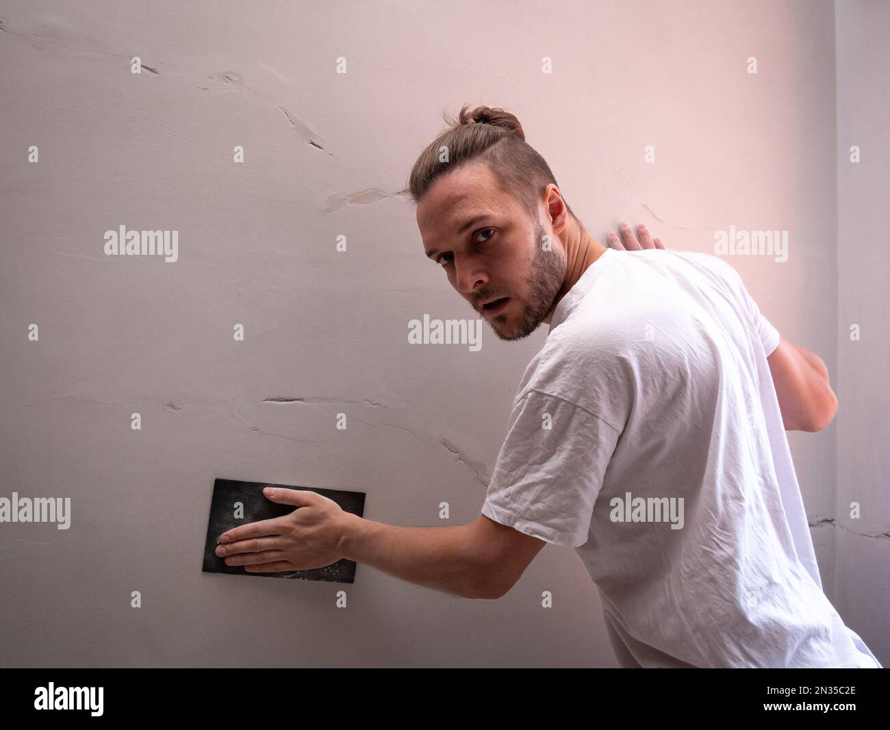 White Man Repairs White Wall Using Sandpaper Stock Photo - Alamy
