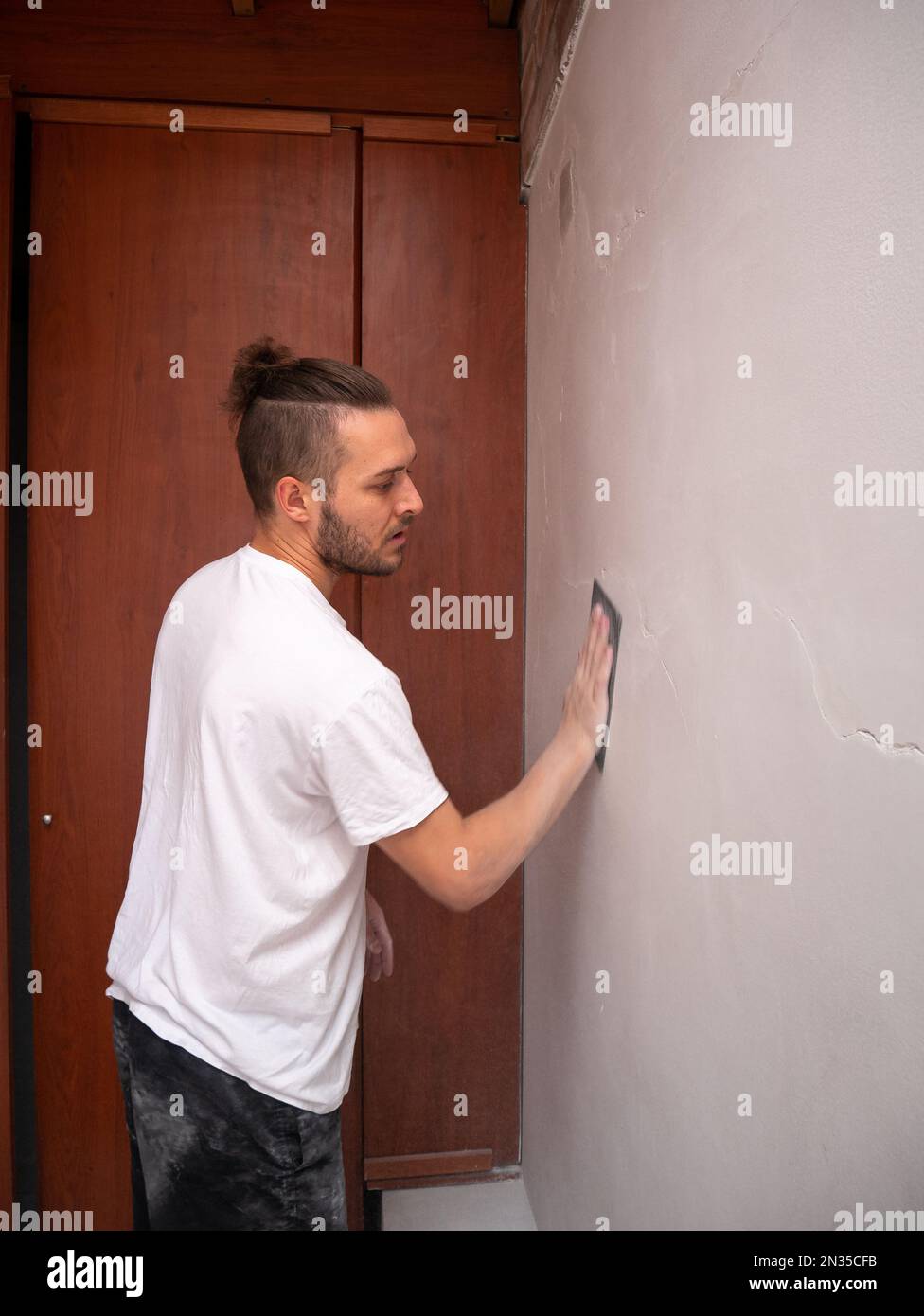 White Man Repairs White Wall Using Sandpaper Stock Photo - Alamy