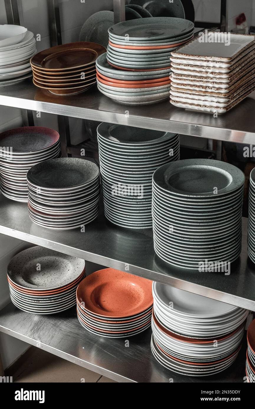 Clean dishes in the restaurant on the shelves. Multicolored plates in ...