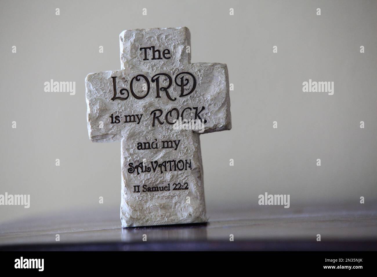 A soft focus of a carved rock cross with a printed bible verse Stock ...