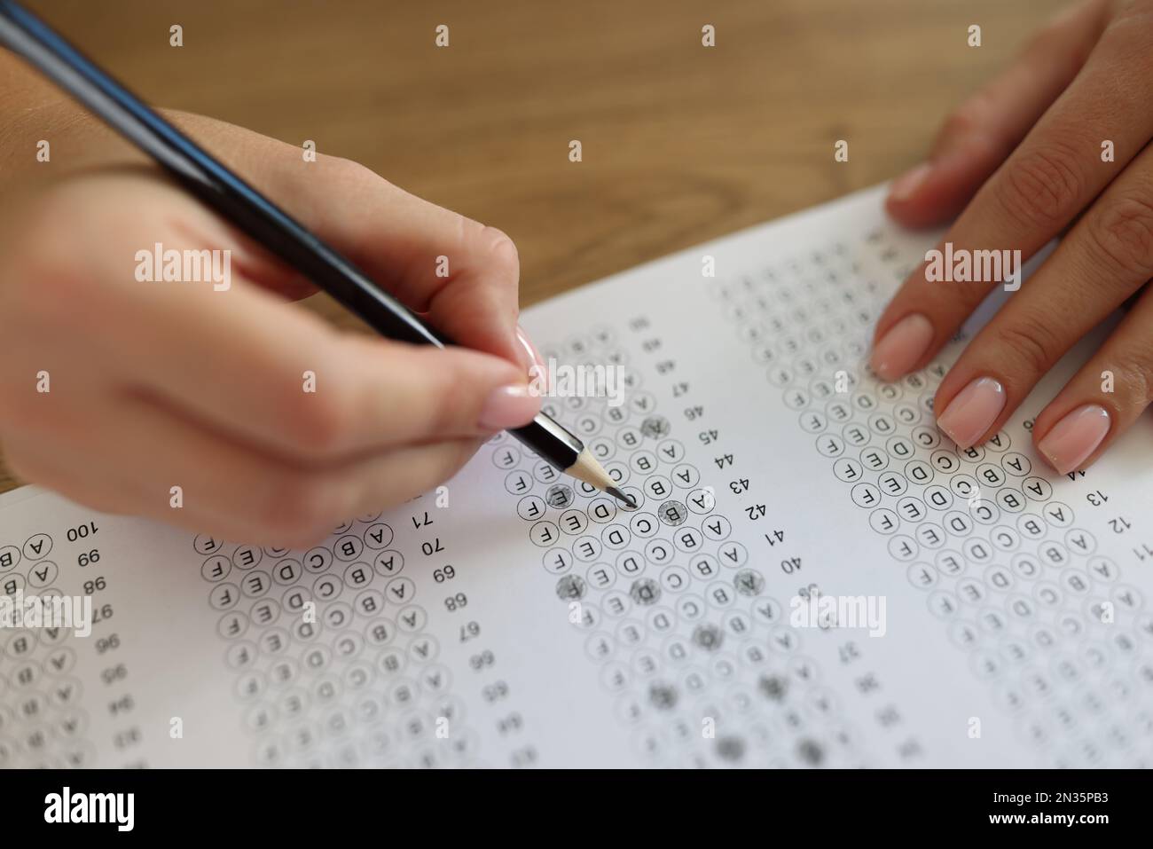 Female student answers test questions with pencil Stock Photo - Alamy