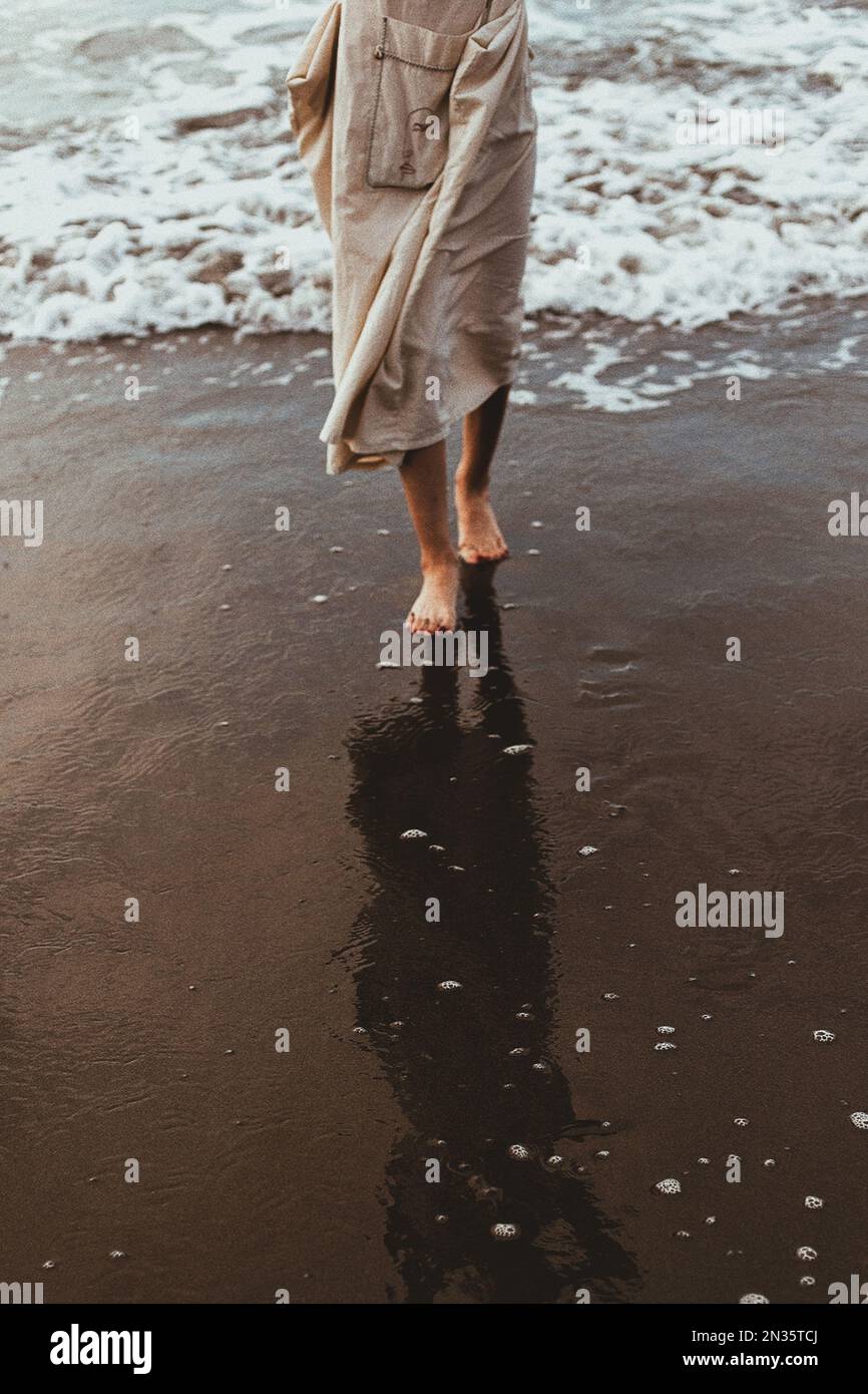 A vertical view of the woman's feet on the sand before sea waves Stock ...
