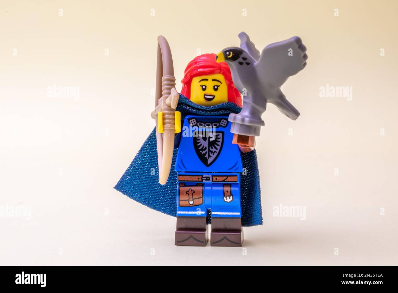 A small Lego figurine in a blue costume with a raven and a bow and ...