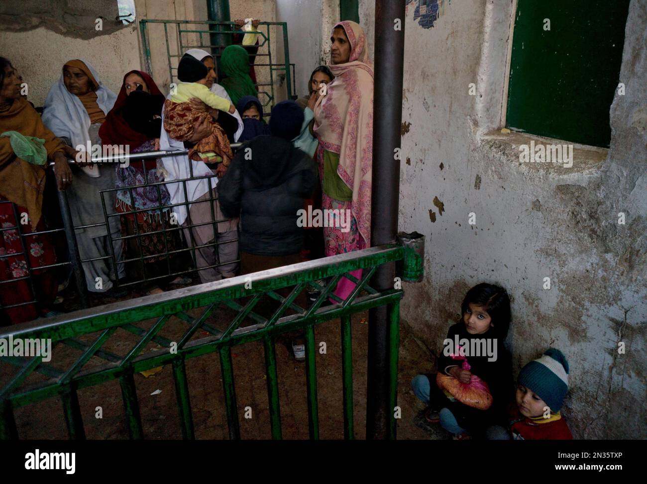 Poor Pakistani families wait for free food distributed at the Barri ...