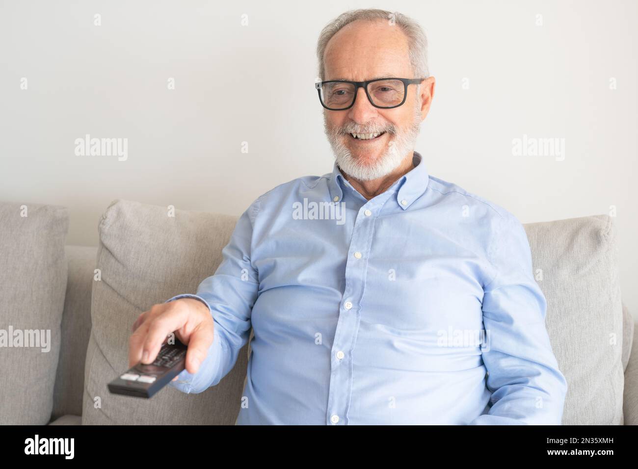 Fat senior man watching TV while sitting on sofa at home. Sedentary ...