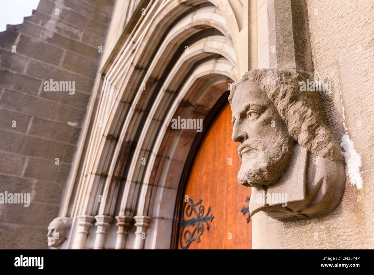Ornately carved stone head and face on the outside of a church entrance ...
