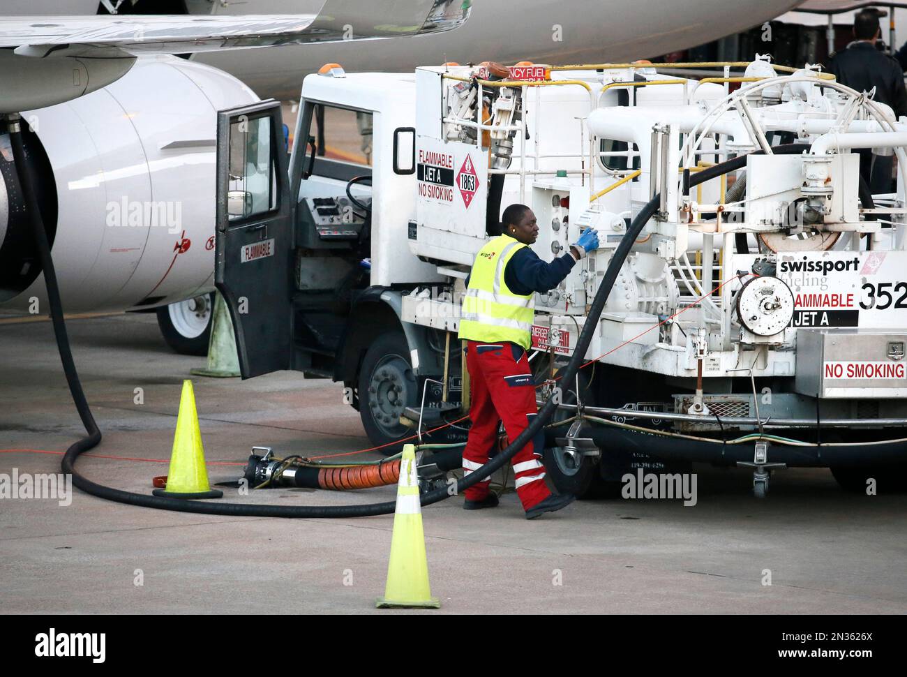 A Swissport employee prepares to fuel a jet parked at a gate at a at ...