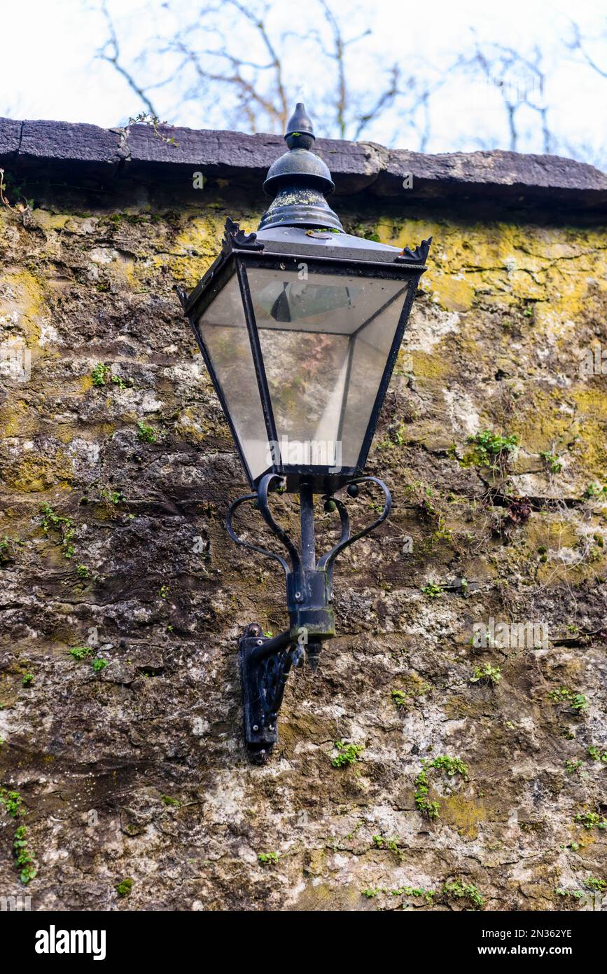 Old fashioned wrought iron and glass wall lamp, fited witth a modern ...