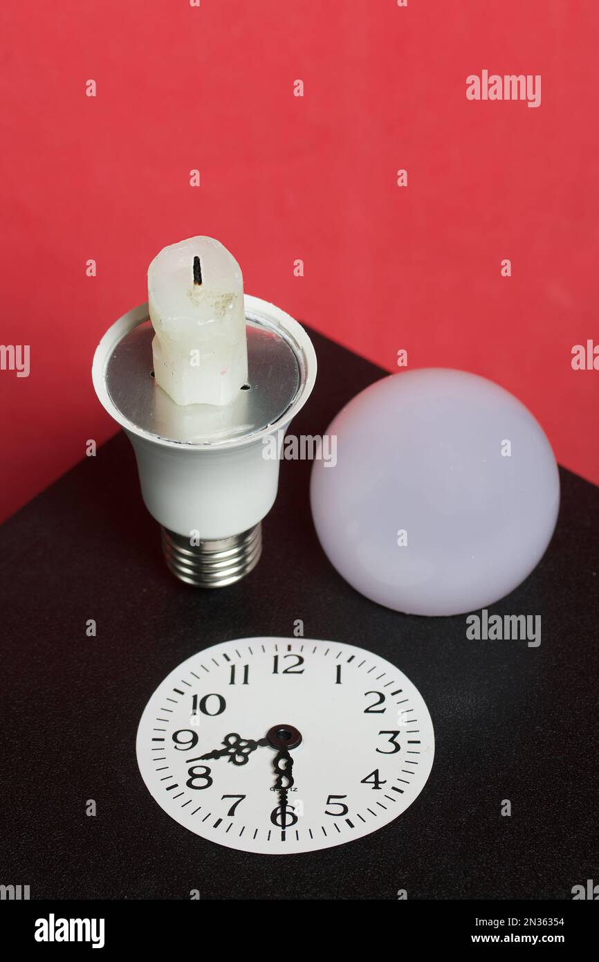 Light bulb with candle stub. Clock face with arrows at 20:30. Global ...