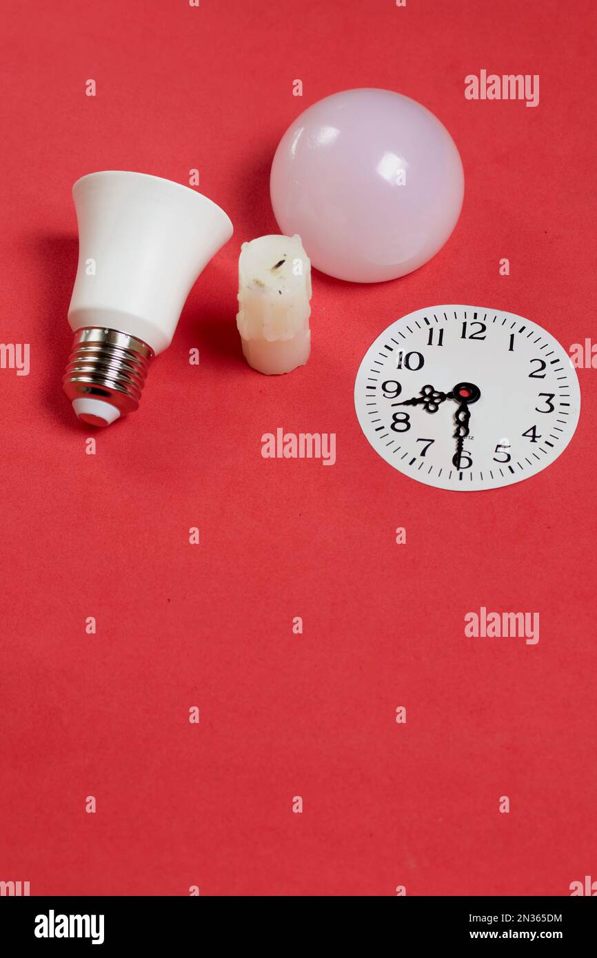Disassembled LED bulb. Nearby is a candle stub. Clock face with arrows ...