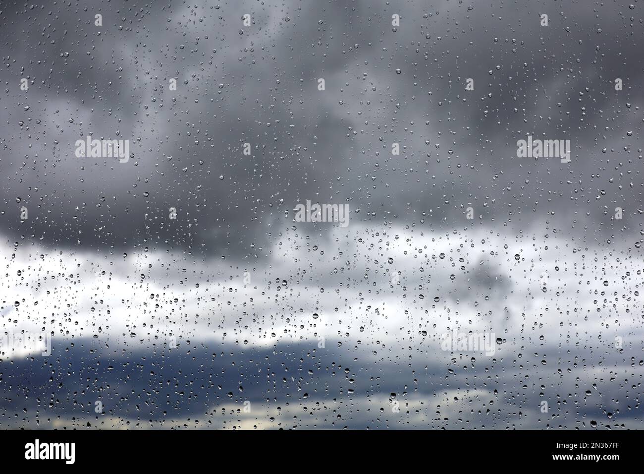 Raindrops on window glass on blurred background of sky with storm ...