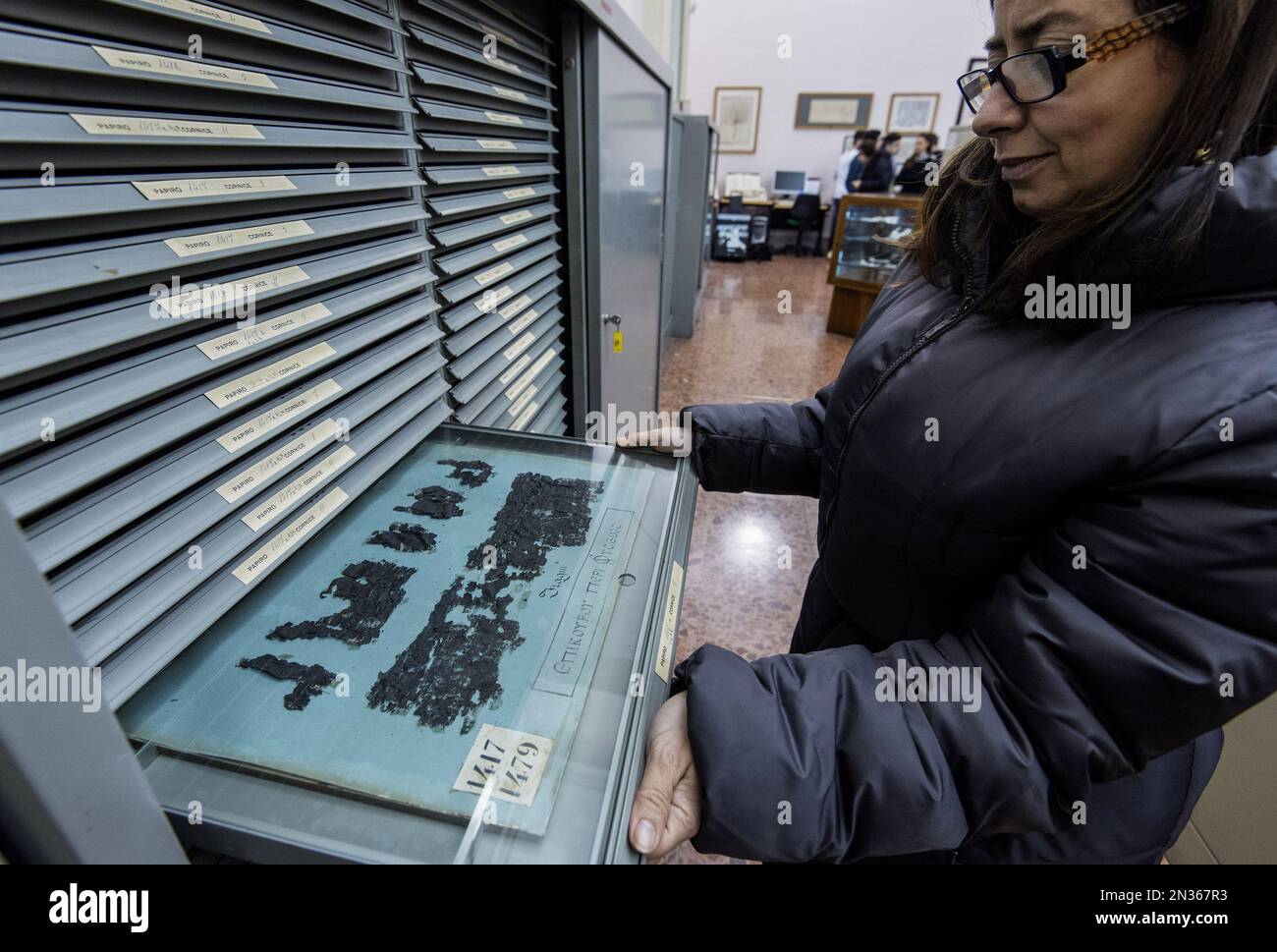 A woman shows the remains of an ancient papyrus at the Naples' National ...