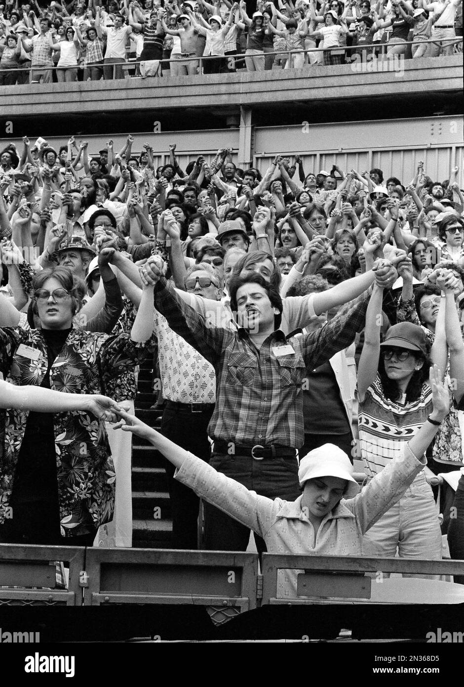 Audience members raise their arms and sing during Jesus Day ...