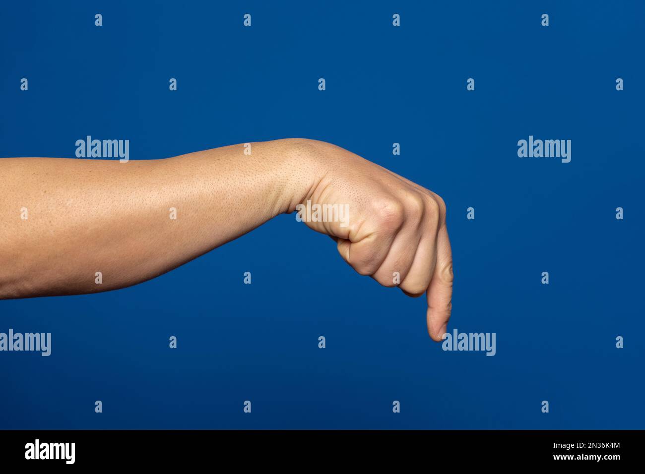 Strong hand of man pointing index finger down isolated on blue ...