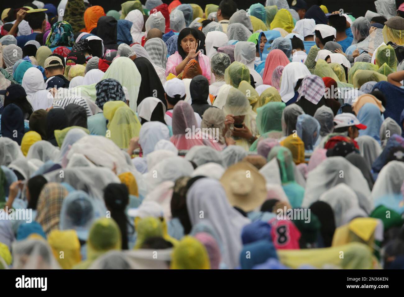 A Filipino woman makes hand signals as rain pours during the visit of ...