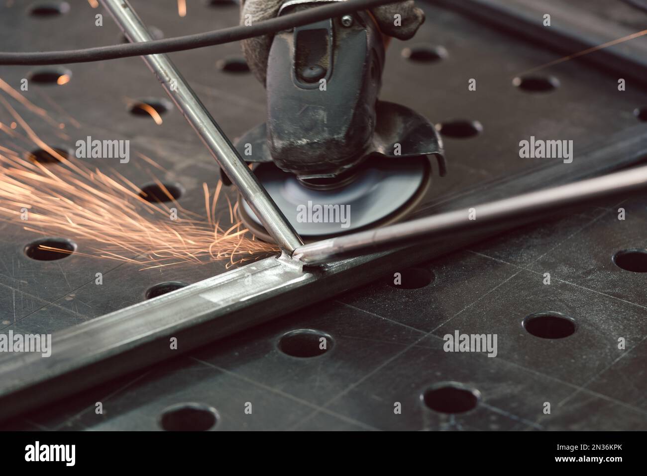 Worker in metal factory grinding workpiece with sparks flying Stock ...