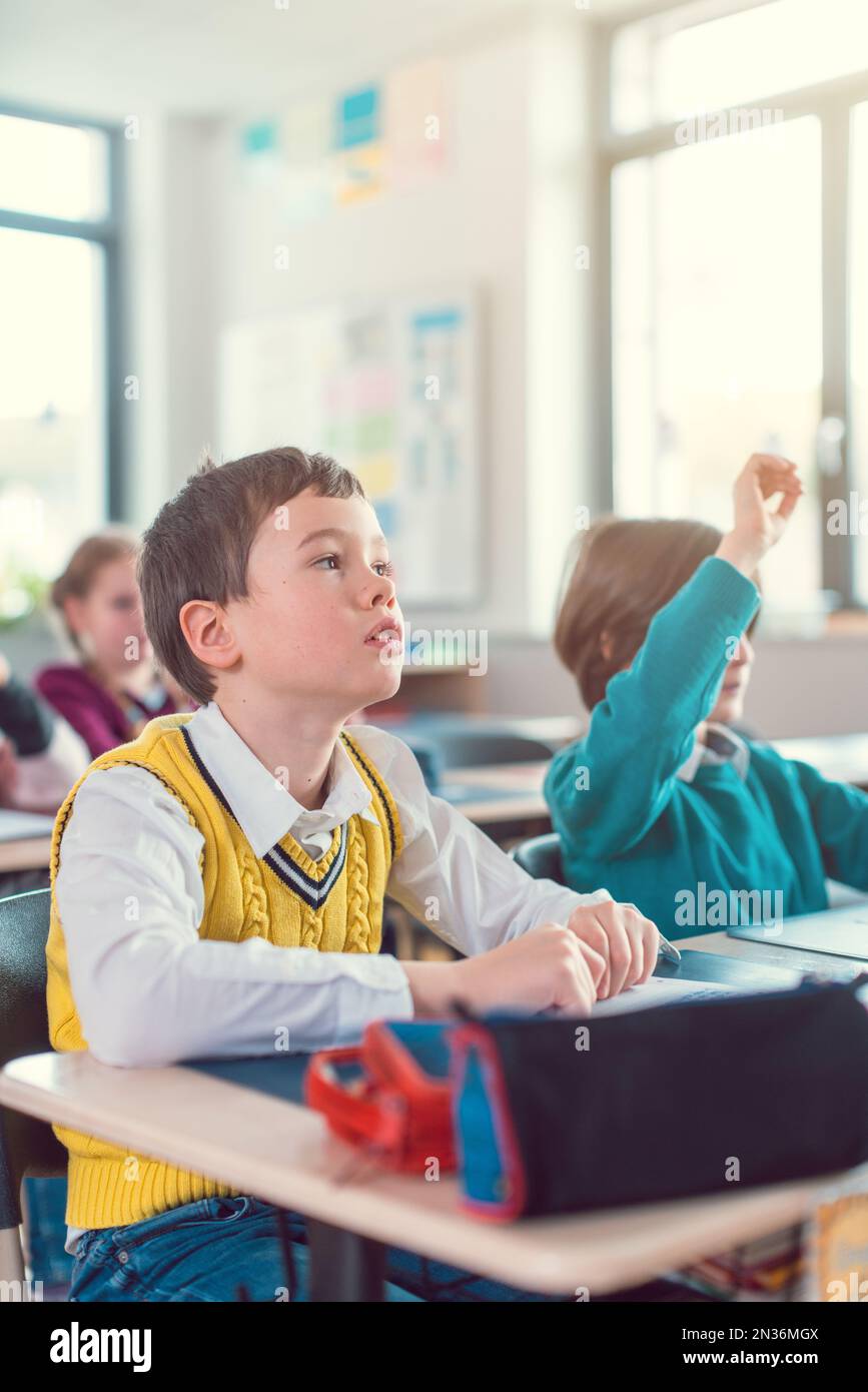 Boy student in class knowing an answer raising his hand Stock Photo - Alamy