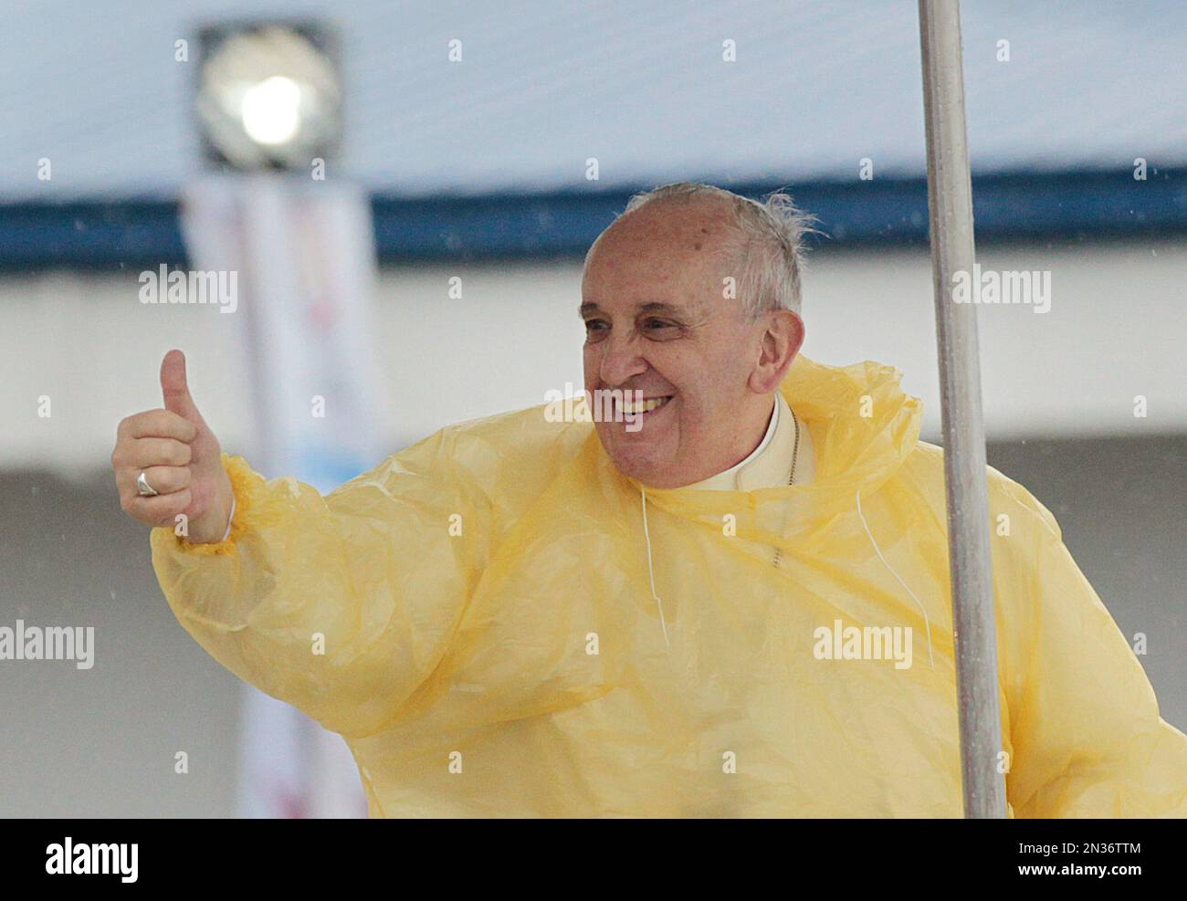 Wearing a yellow raincoat, Pope Francis gives a thumbs up to the ...