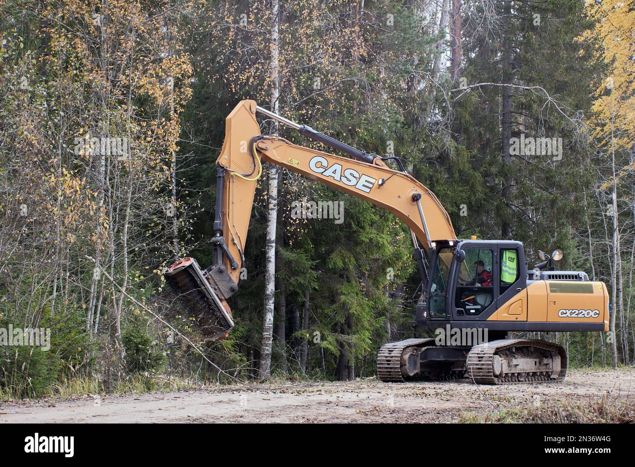 An excavator mulcher with an attachment mulching head clears roadside ...