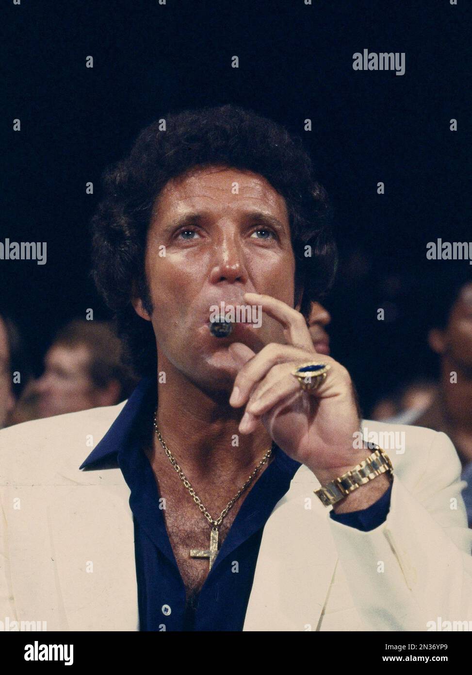 Singer Tom Jones smokes a cigar as he attends the boxing match between ...