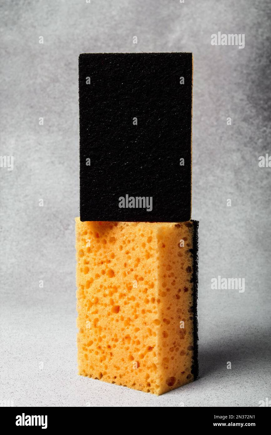 A yellow dishwashing sponge is shown from the soft and hard side ...