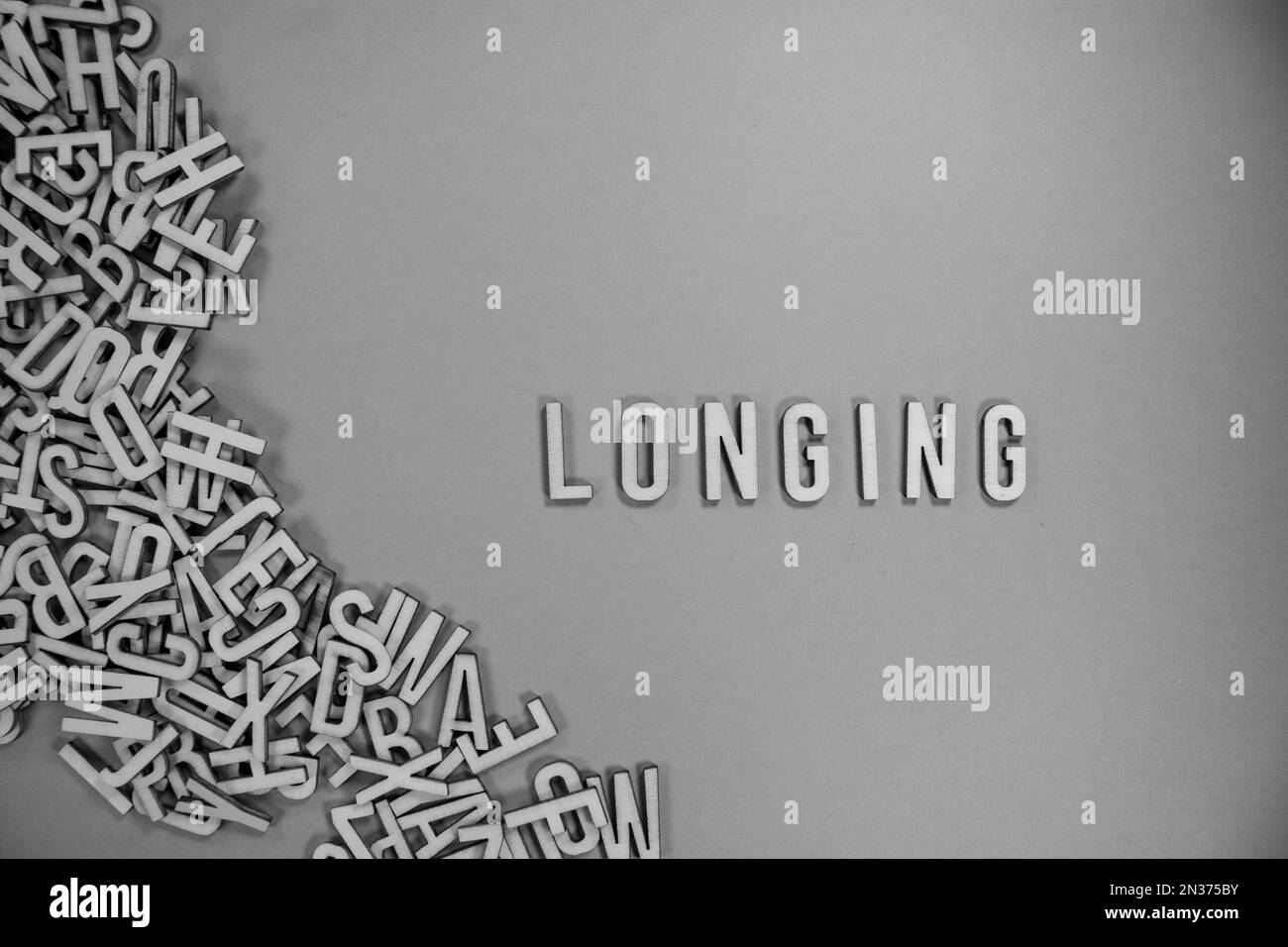 LONGING in wooden English language capital letters spilling from a pile ...