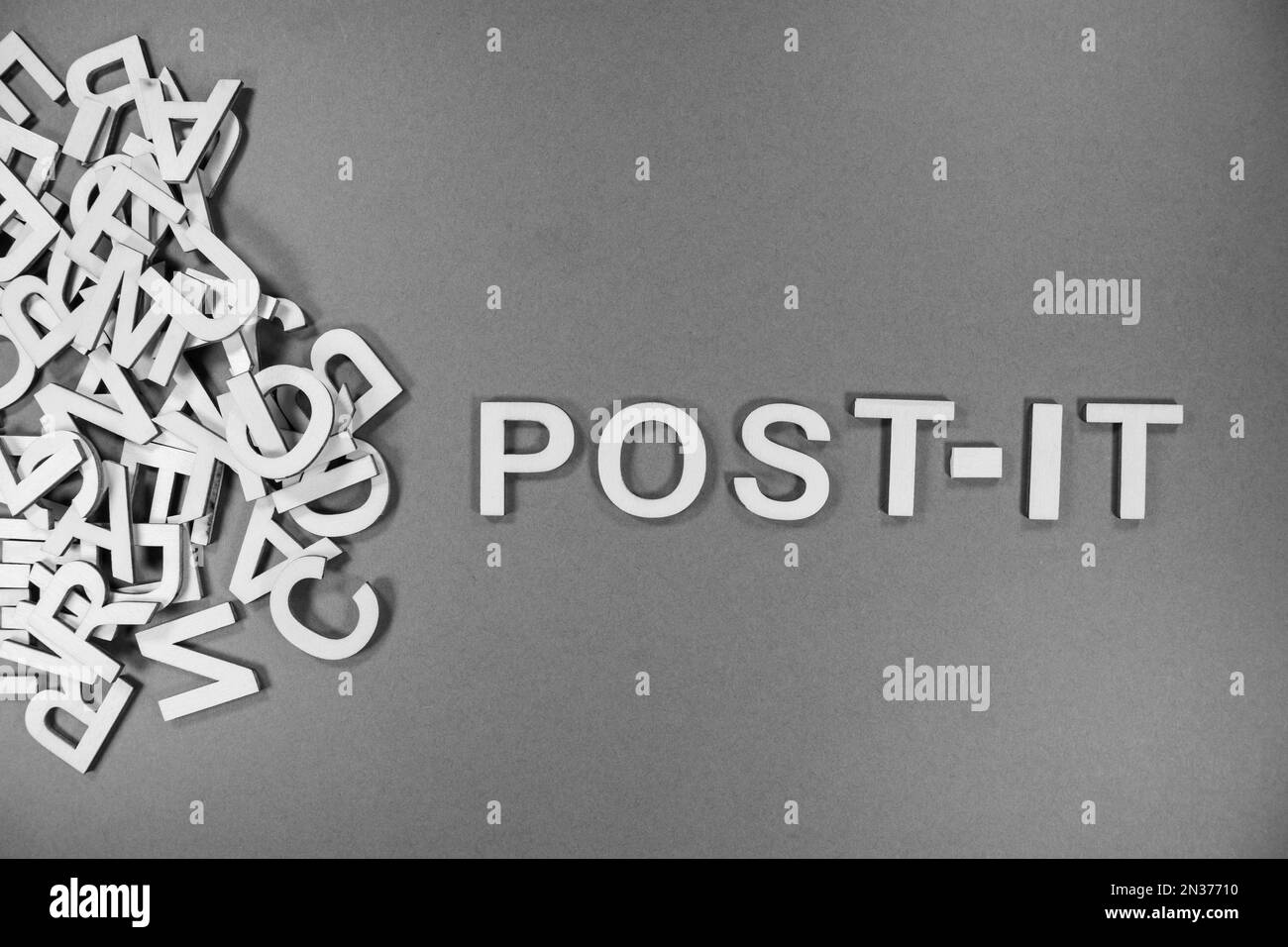 POST-IT in wooden English language capital letters spilling from a pile ...