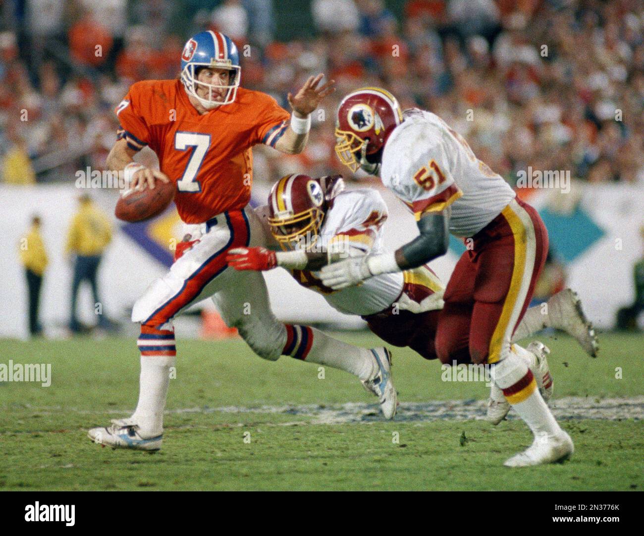 Denver Broncos quarterback John Elway (7) scrambles under pressure from ...