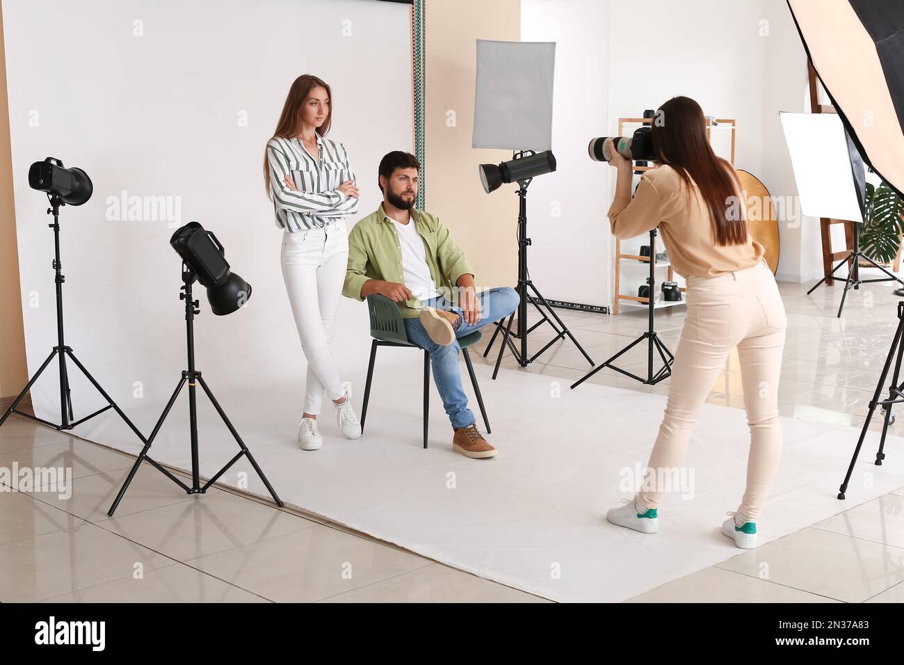 Female photographer taking picture of models in studio Stock Photo - Alamy