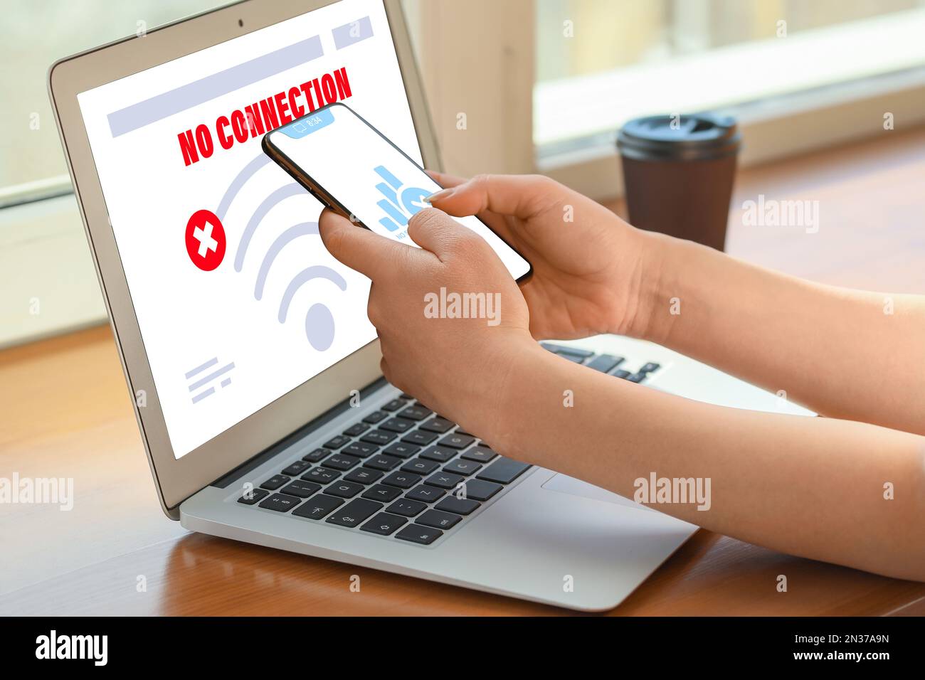Woman with mobile phone and laptop with text NO CONNECTION on screen at ...