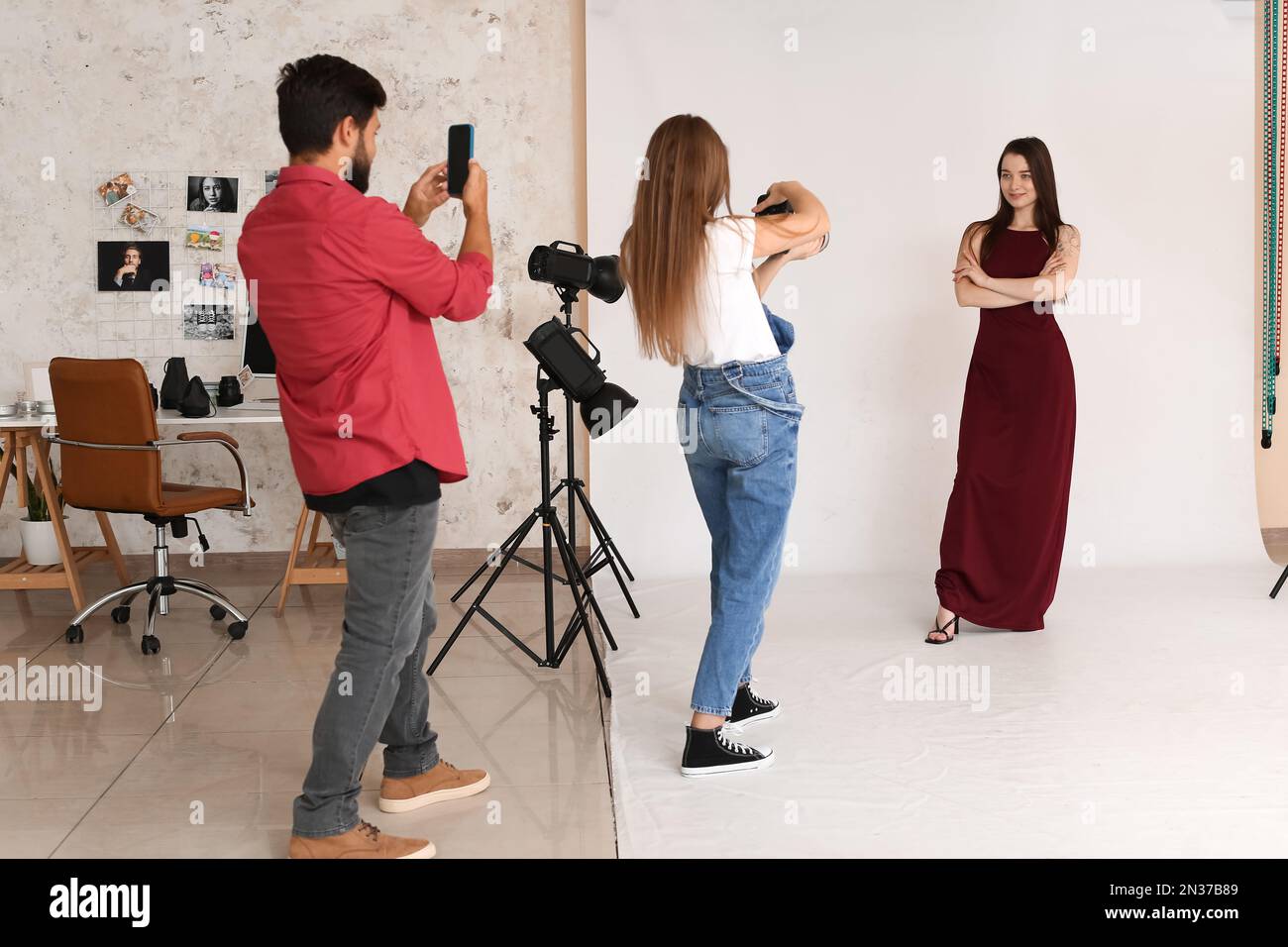 Female photographer and her assistant working with beautiful model in ...