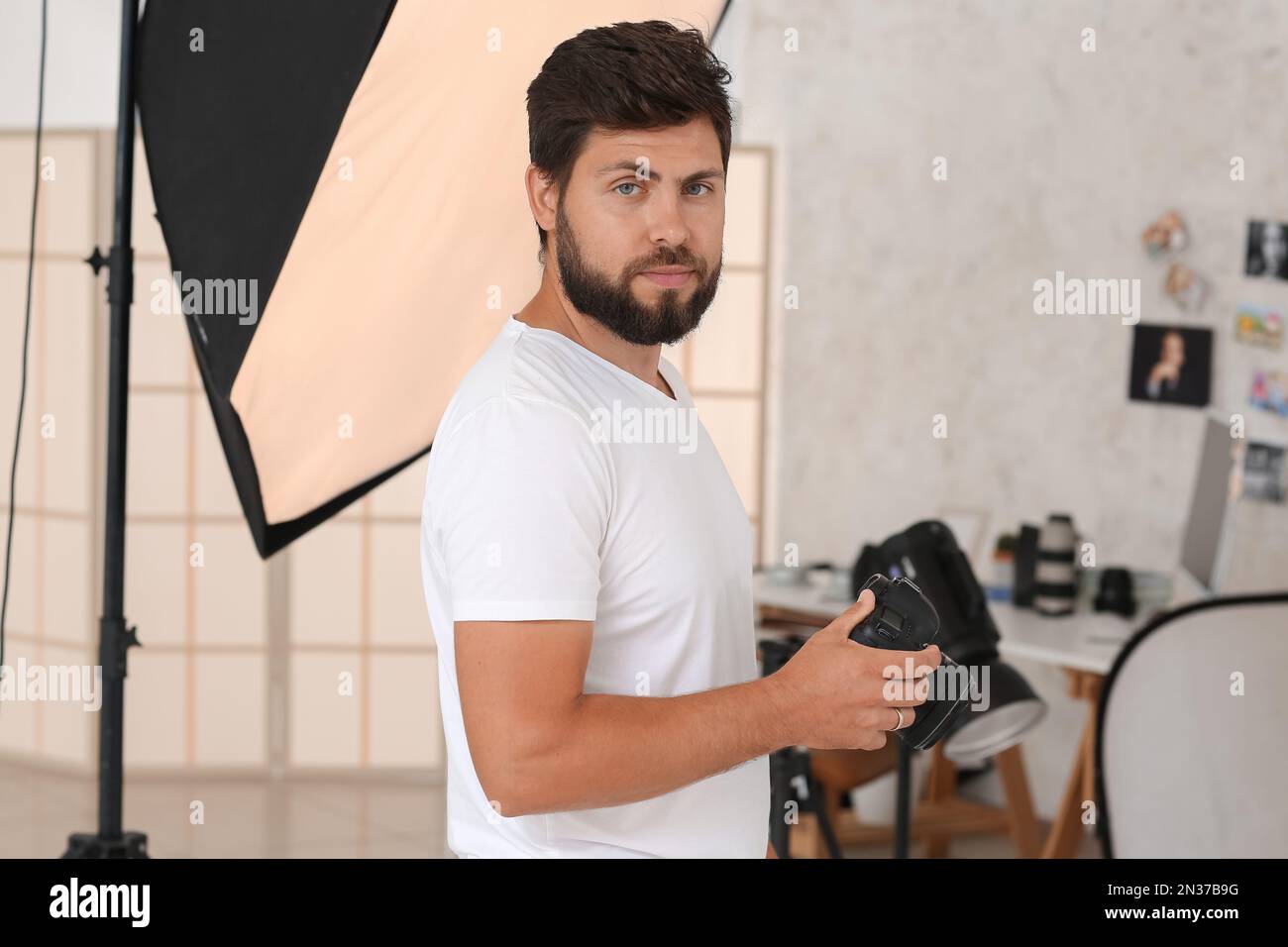 Handsome photographer with camera in studio Stock Photo - Alamy