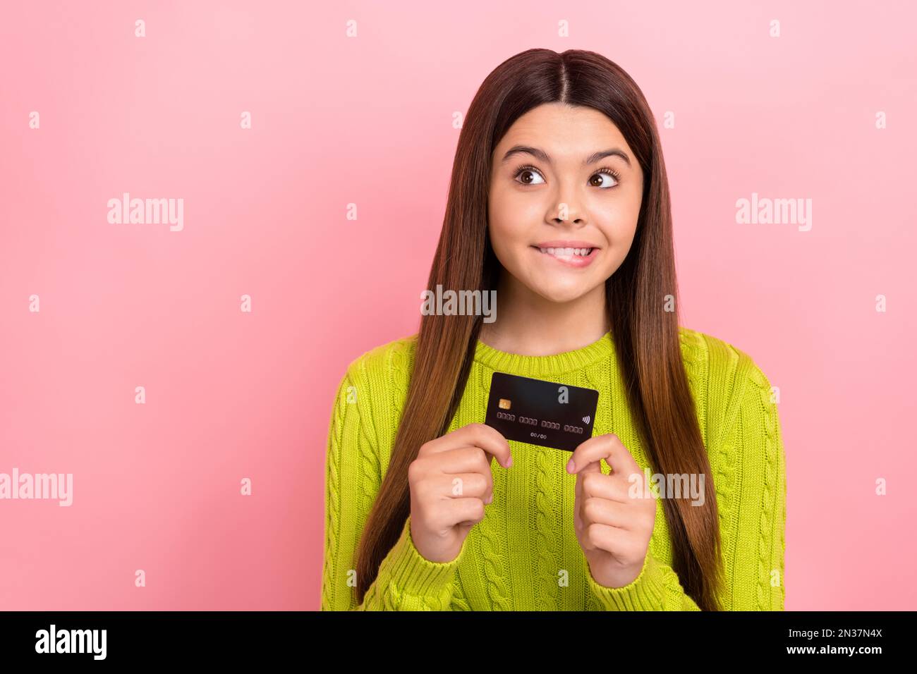 Portrait of cute positive girl hold debit card biting lip look empty ...