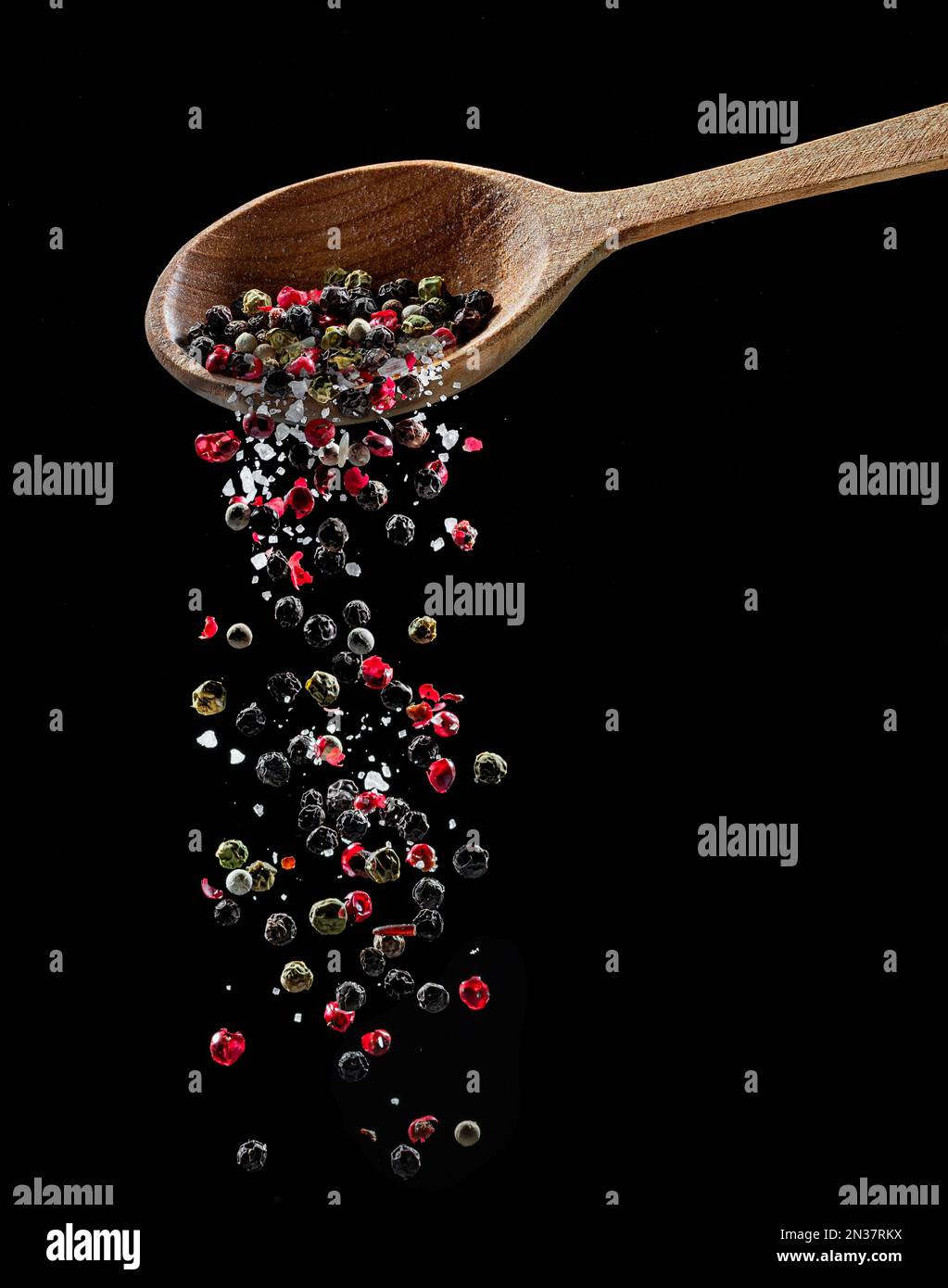Mix of different peppercorns and salt falling down from the wooden ...