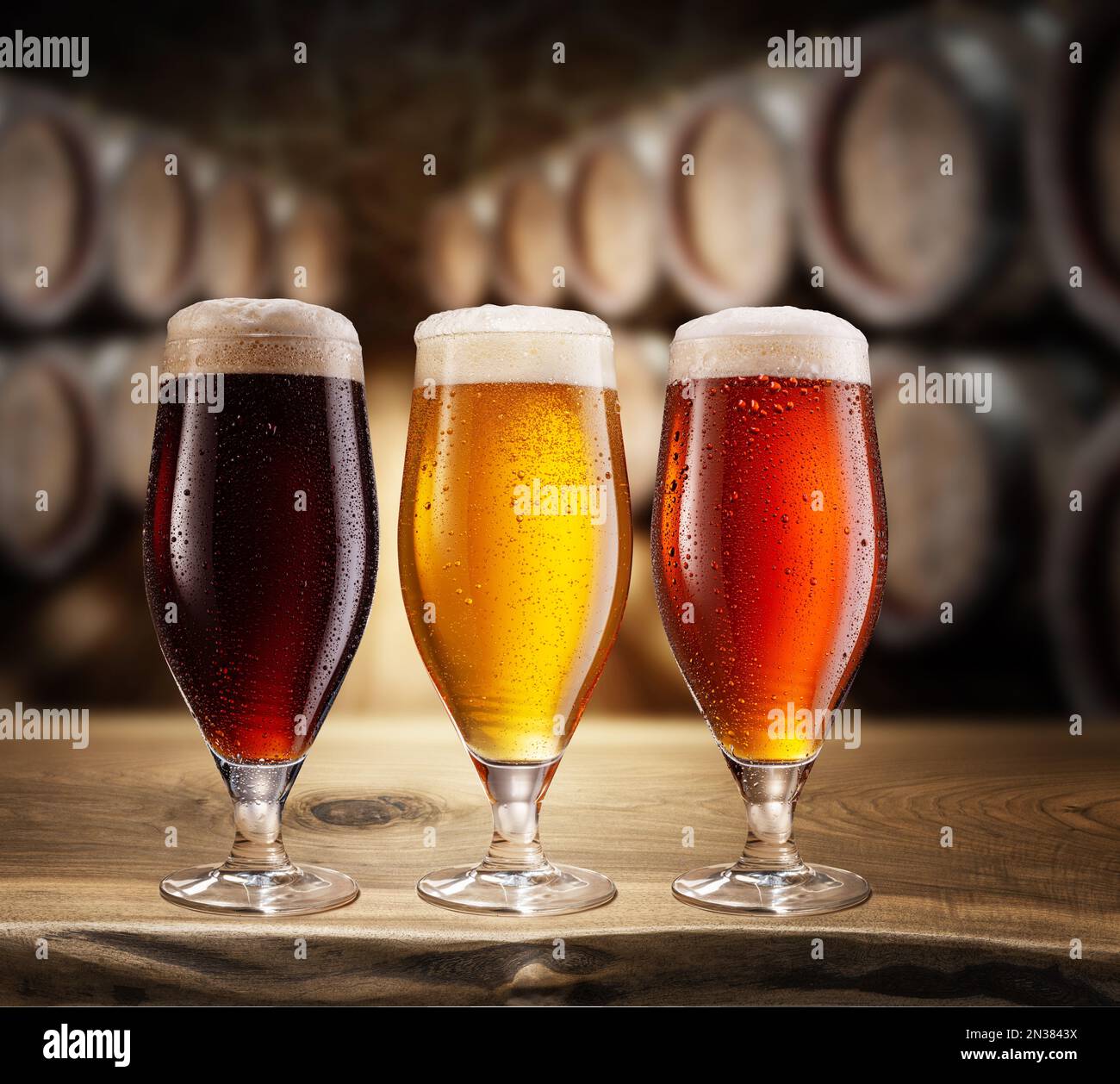 Three type of beer with foam head on wooden table. Blurred brewery ...