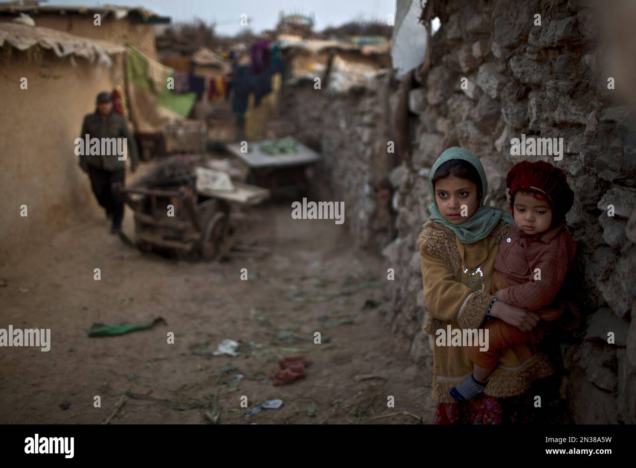 An Afghan refugee carries her sister in an alley of a slum on the ...