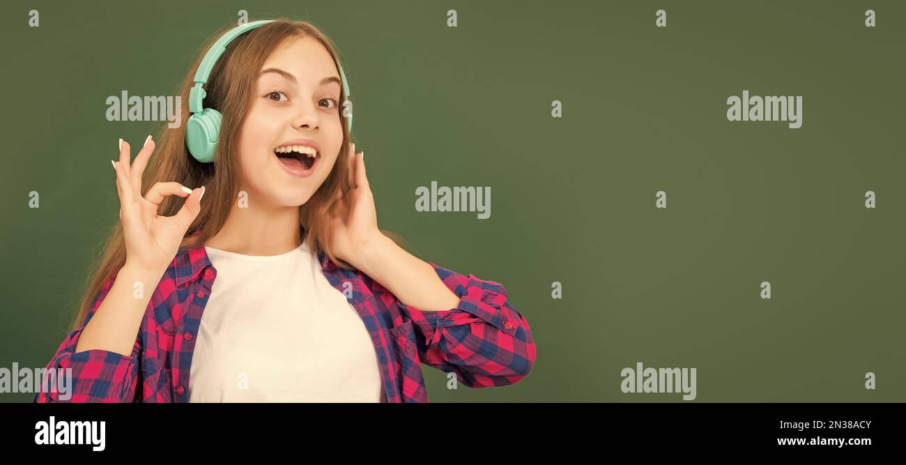 cheerful child listen music in headphones at blackboard. Portrait of ...