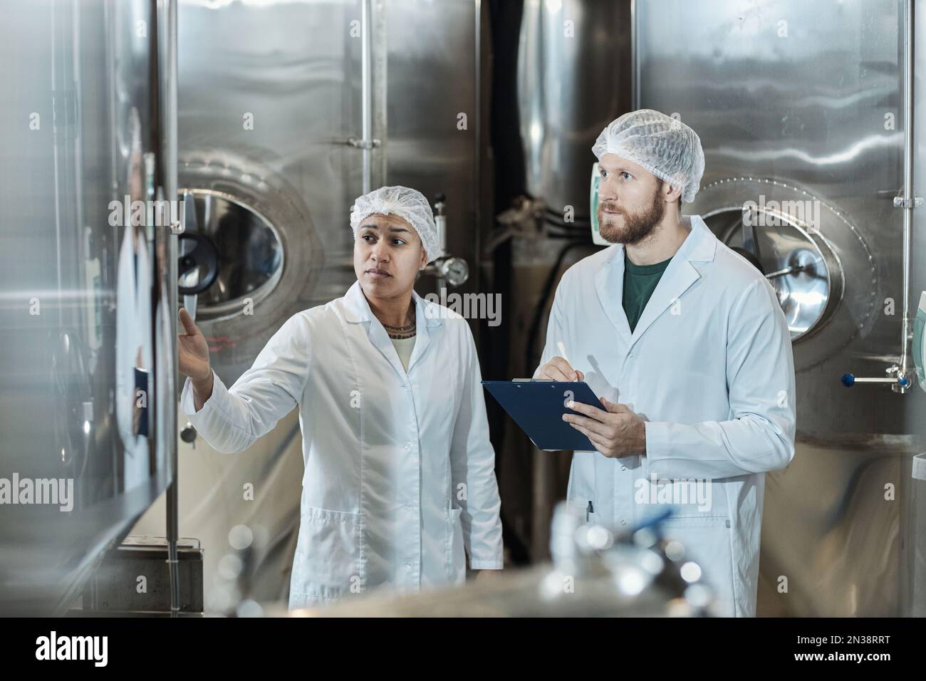 Portrait of two workers wearing lab coats in food factory workshop ...