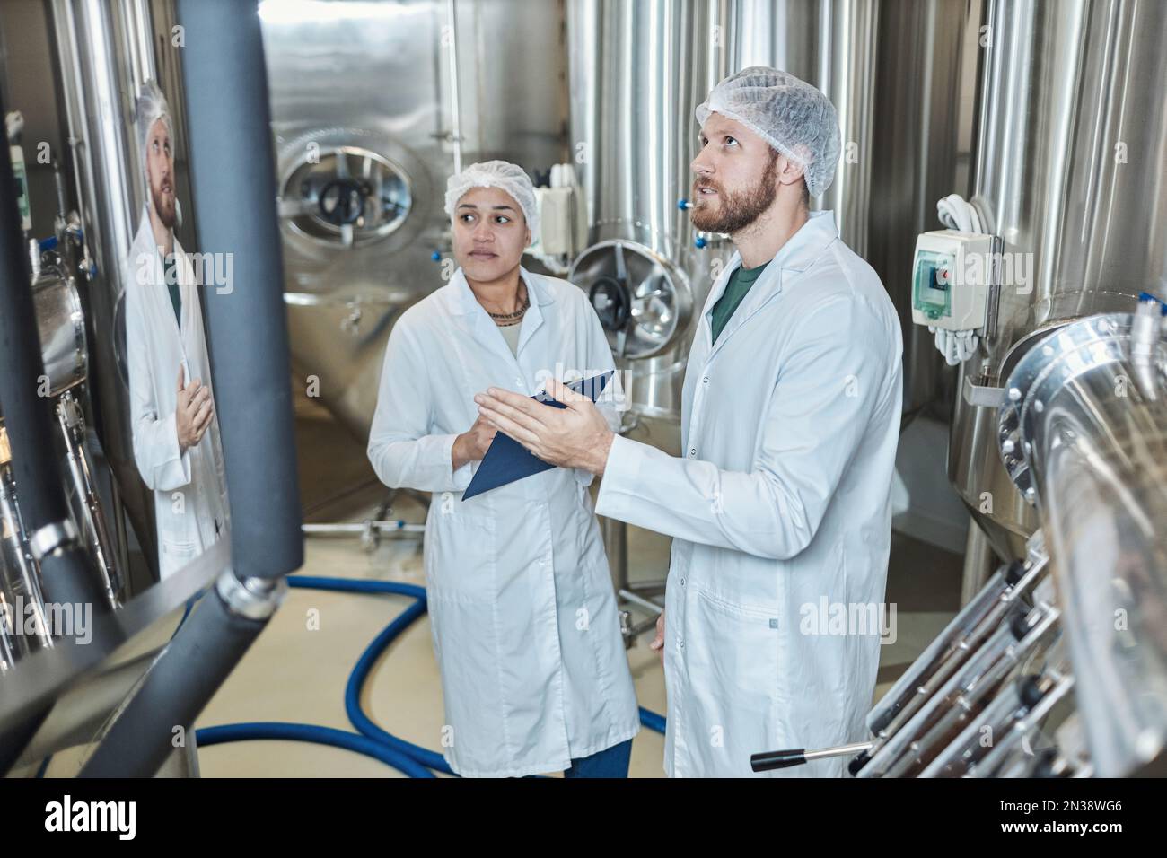 Portrait of two people wearing lab coats inspecting food factory ...