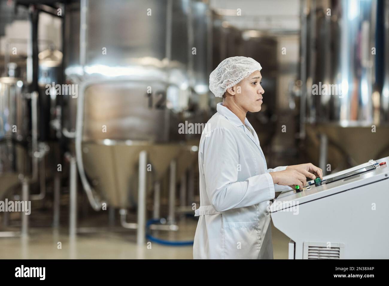 Side view portrait of female worker wearing lab coat operating ...