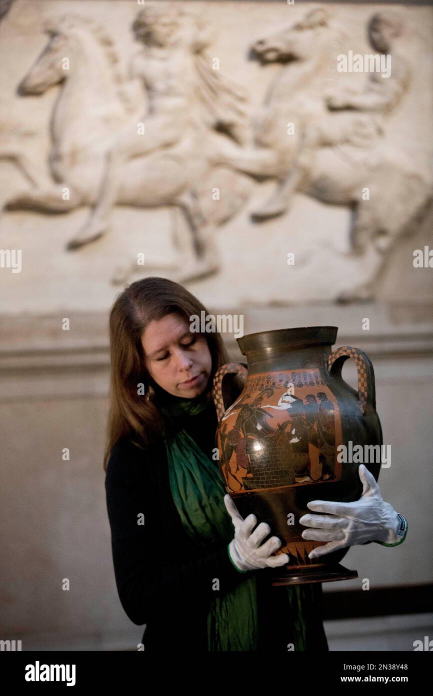 A museum employee poses for photographs with a circa 550-540BC amphora ...