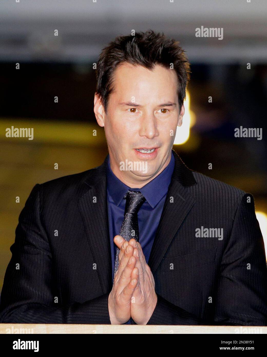 Actor Keanu Reeves puts his hands together in a gesture to greet his ...