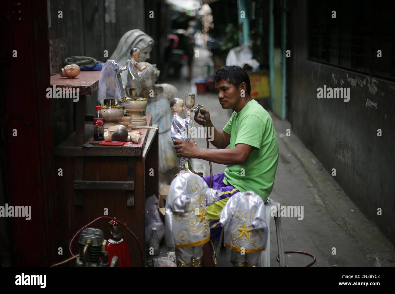 A Filipino man paints statues of the baby Jesus in Manila, Philippines ...
