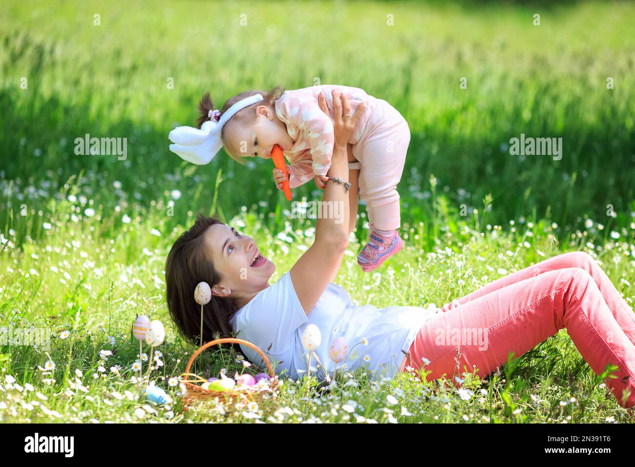One year old girl playing with mother and egg hunt on Easter. Mom ...