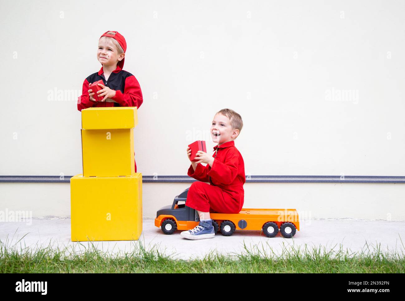 Two little courier boys in red uniform with yellow cardboard boxes and ...