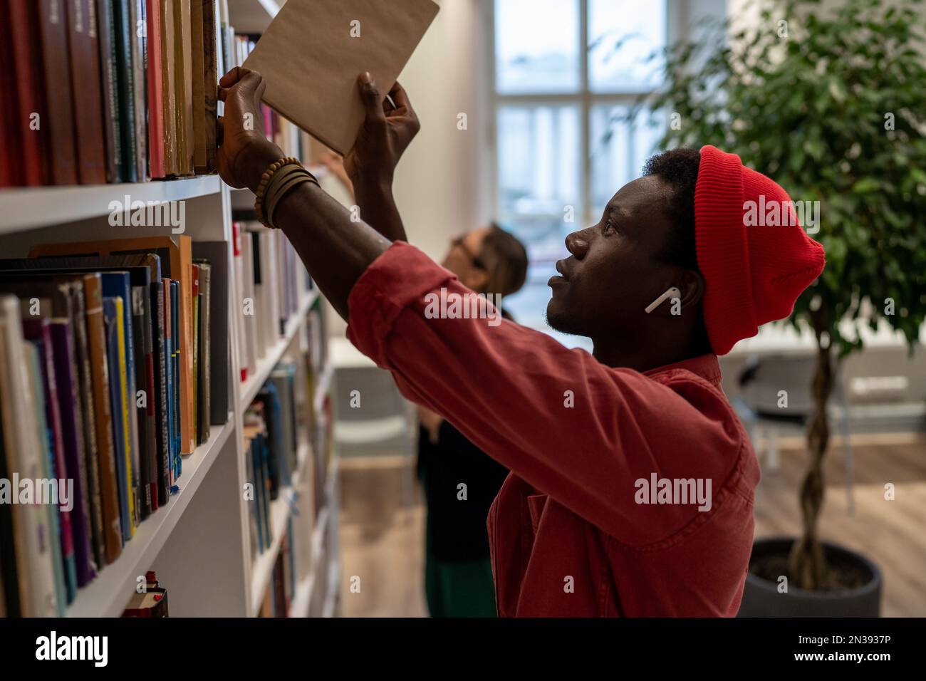 Concentrated African American student man picking books for preparing ...