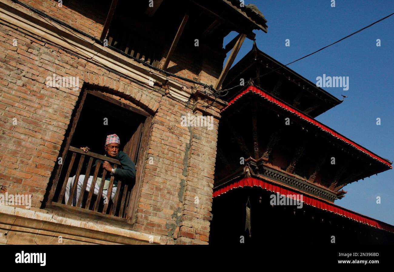 An elderly Nepalese sunbathes by the window of a house near Patan ...