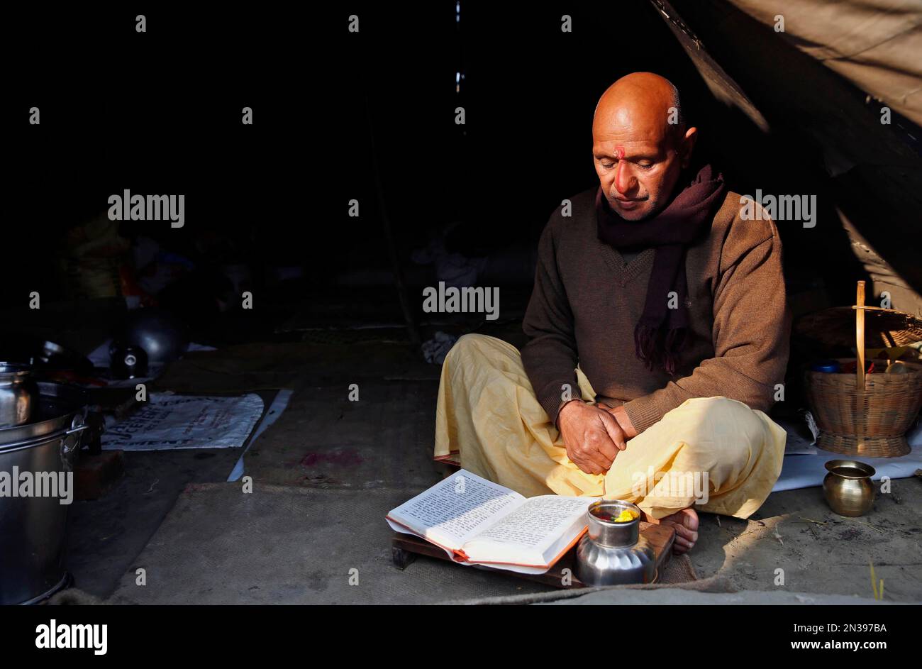 A Kalpavasi devotee reads a holy book outside his rented tents at ...