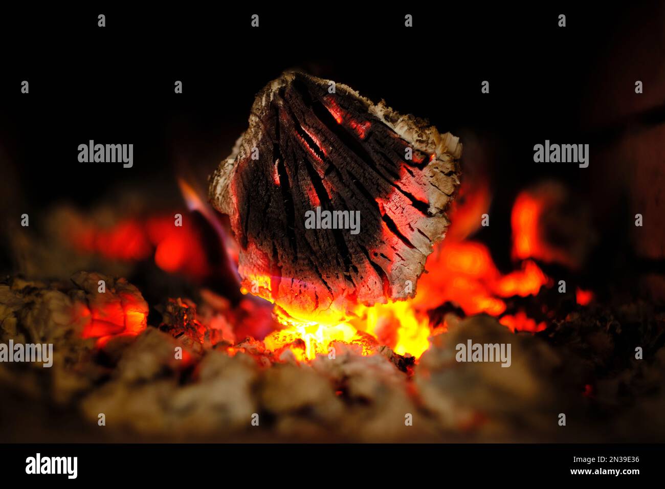 Wood on fire and live coals inside a wood-burning fireplace on a black ...