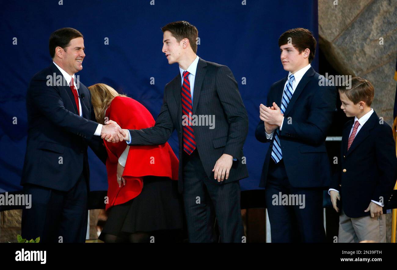Arizona Gov. Doug Ducey, left, smiles as he shakes hands with son Jack ...